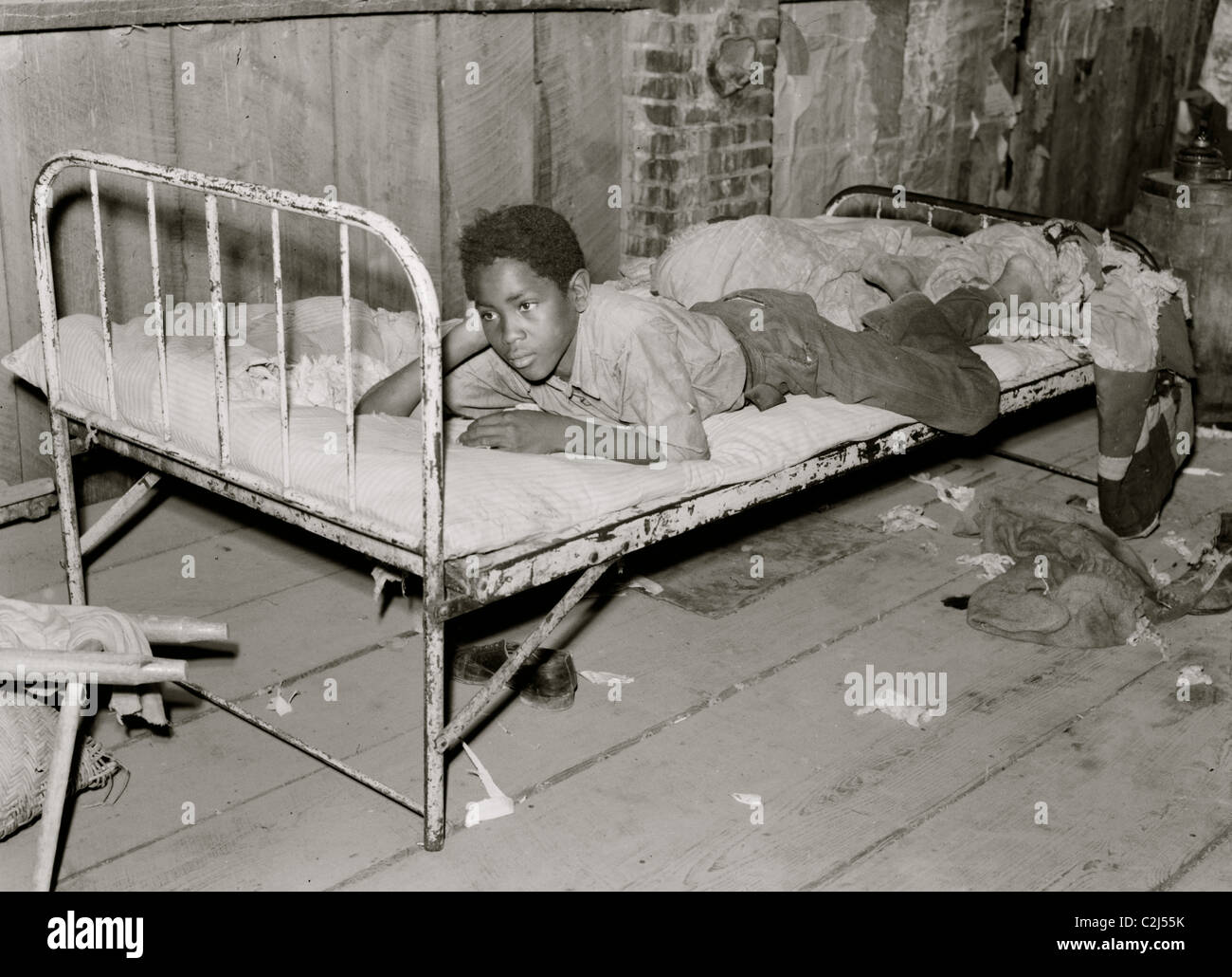 African American Boy resting on bed in attic of sharecropper shack. New ...