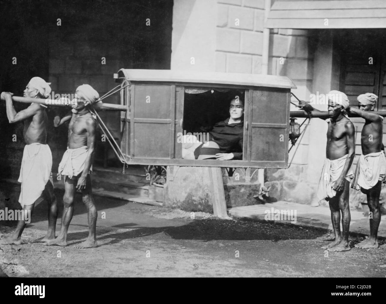Four Indian Porters Carry A Westerner In A Palanquin Or Sedan Chair