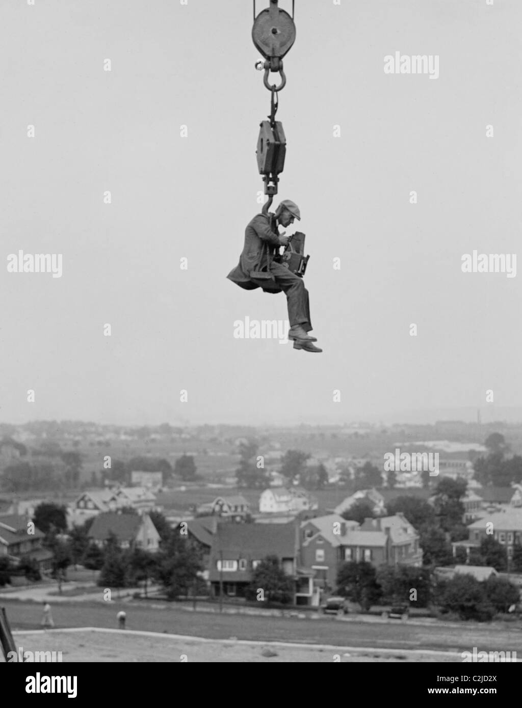 Still Photographer hangs suspended high above the ground on the hook of ...