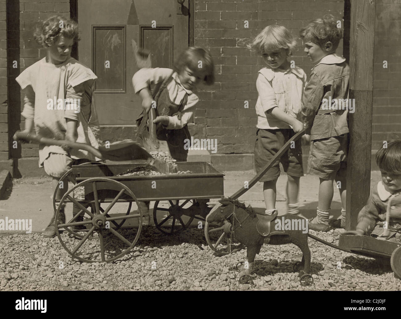 Children Load stones in Wagon with Shovel Stock Photo - Alamy