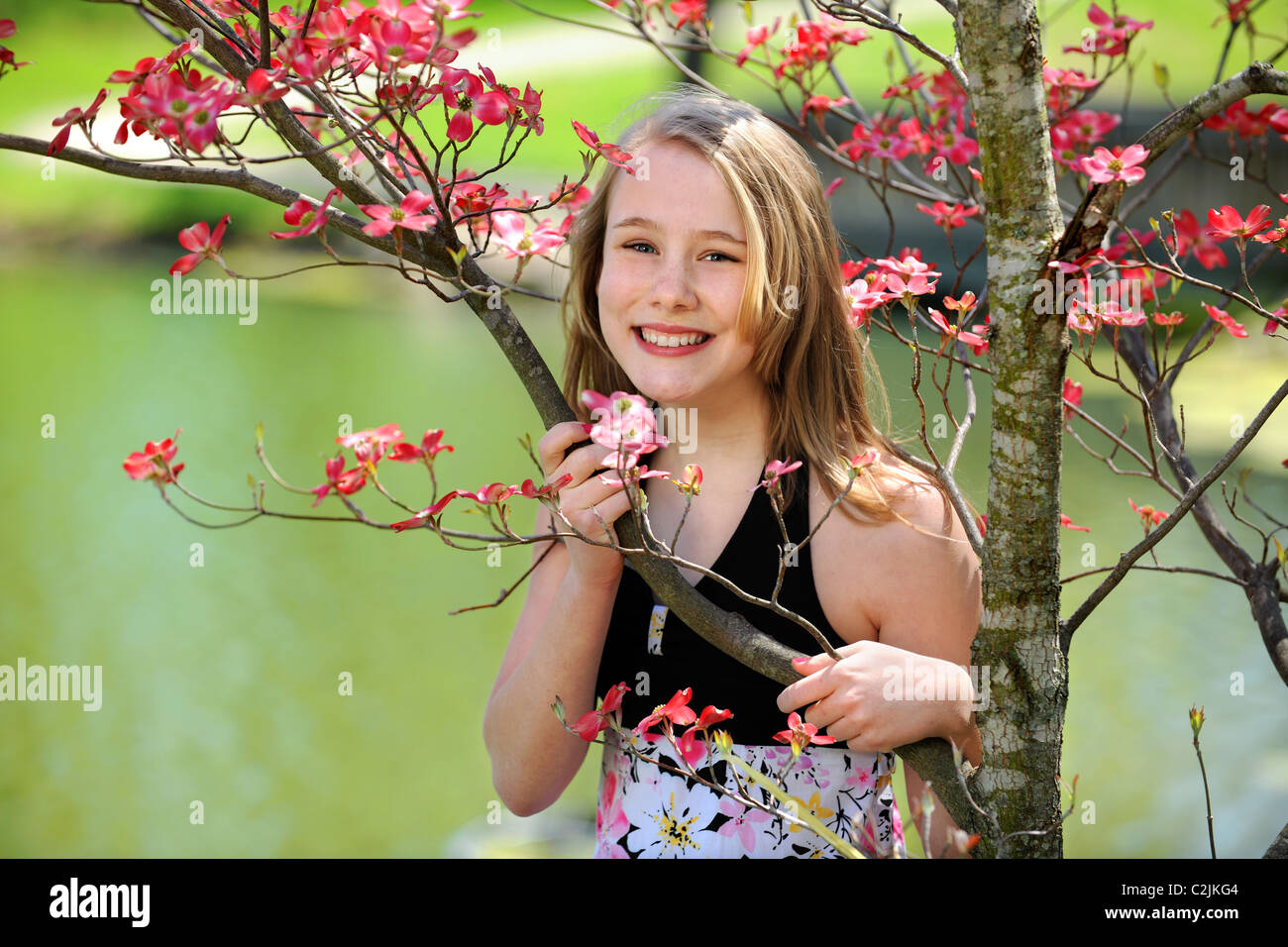 Portrait of teen girl smiling posing outdoors by flowering dogwood tree ...