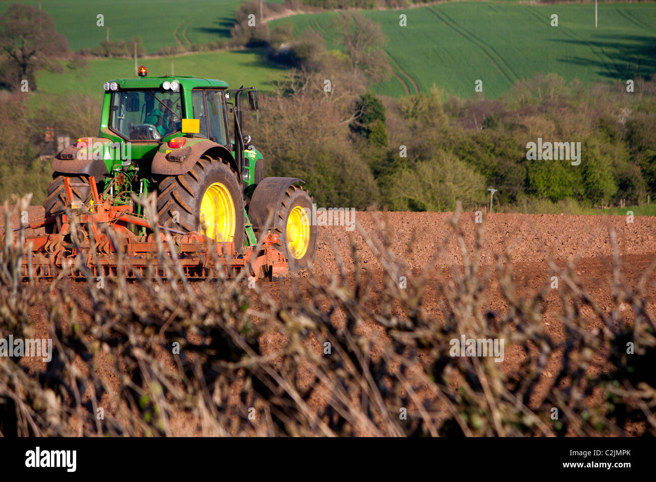 A farmer plowing his farmland field and farm, cultivating the soil ...
