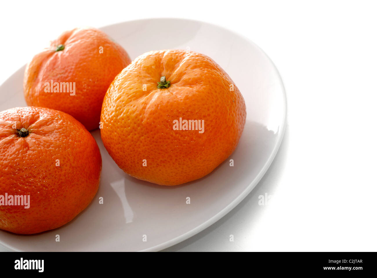 Side view of three fresh juicy tangerines on a white plate on white ...