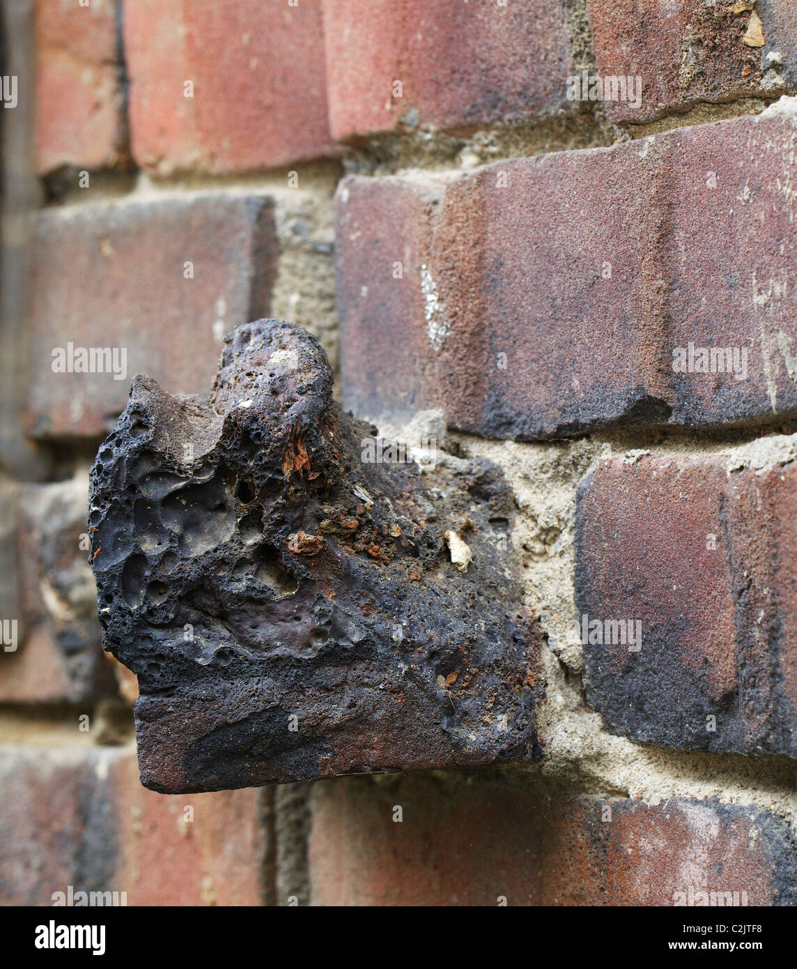 Klinker brick wall with a rogue single deformed brick extending out ...