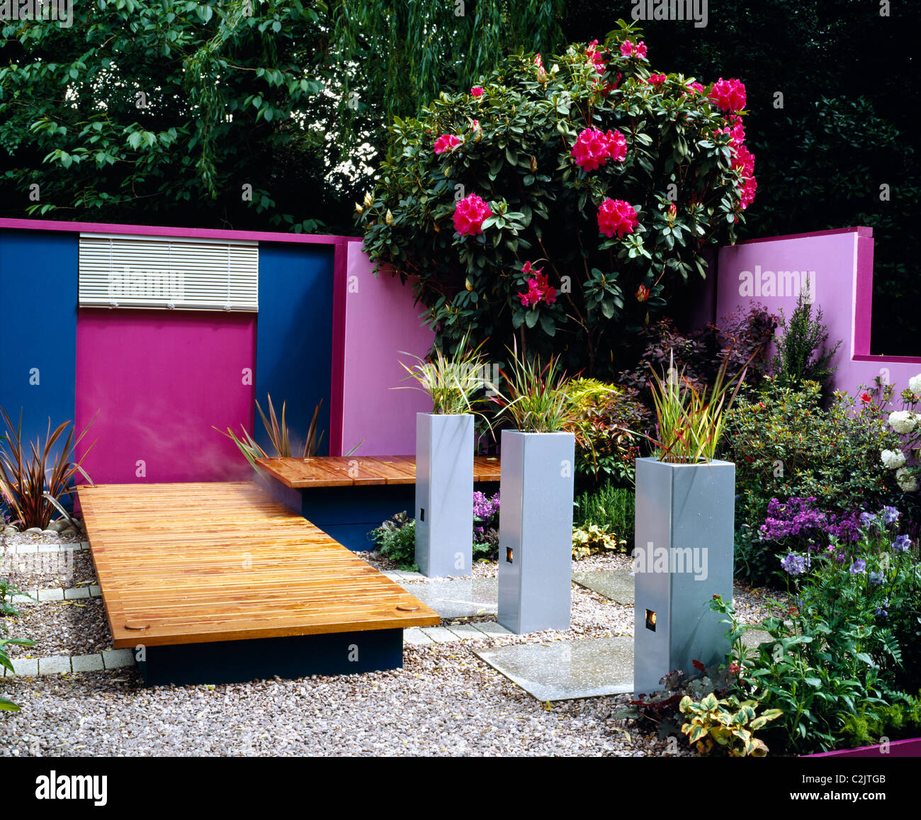 Dramatic courtyard garden with bright coloured walls and raised wooden ...