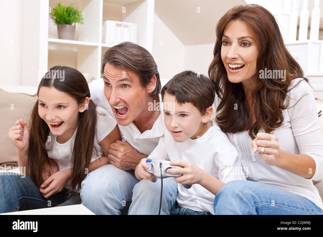 Happy family, parents, son and daughter, having fun playing video ...