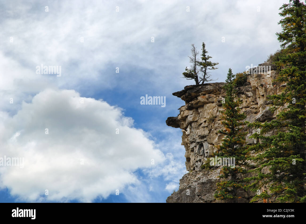 A cliff with clouds behind it in the foothills of the Rocky Mountains ...