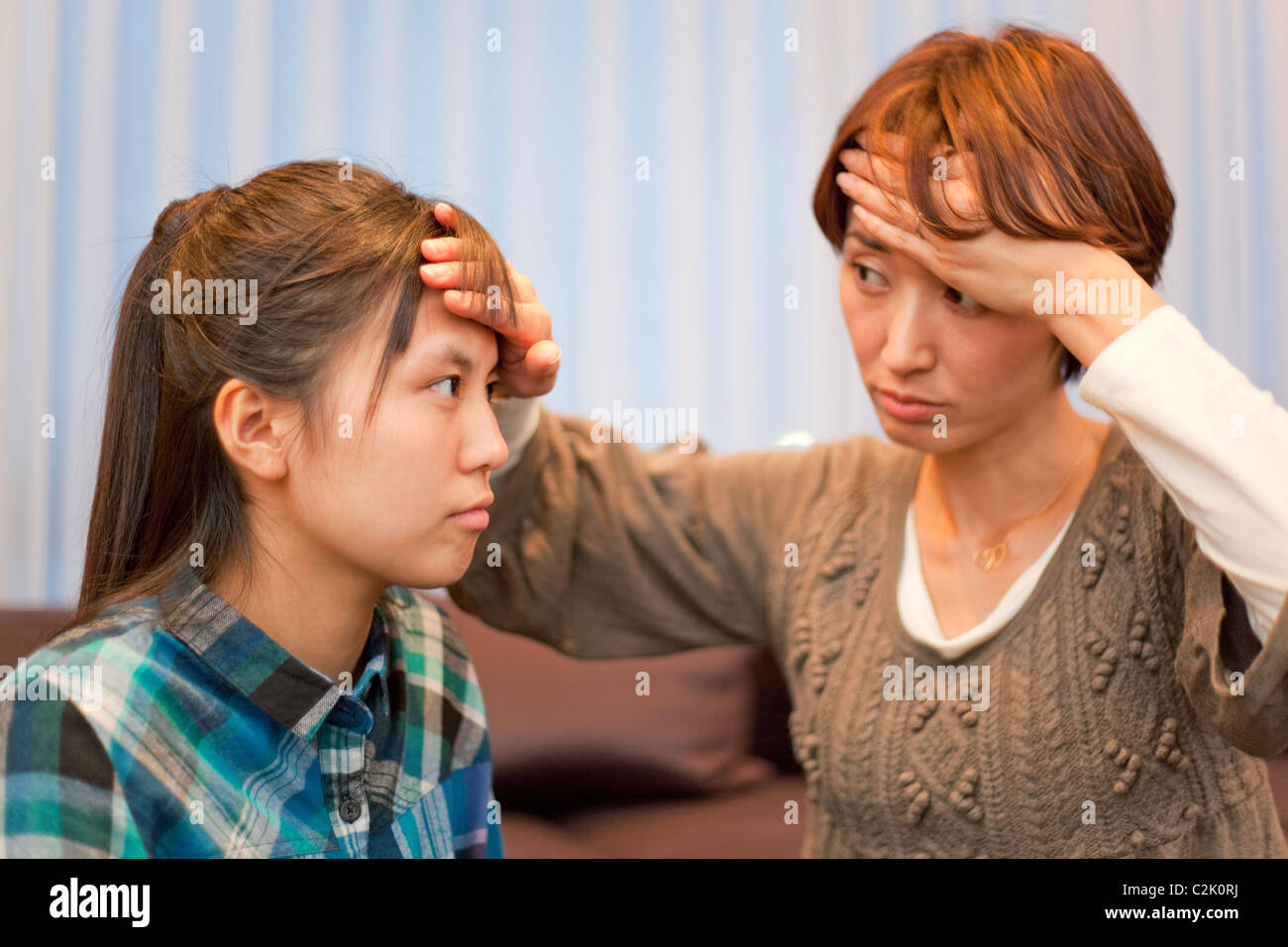 Mother Placing Hands on Own and Daughter's Forehead Stock Photo - Alamy