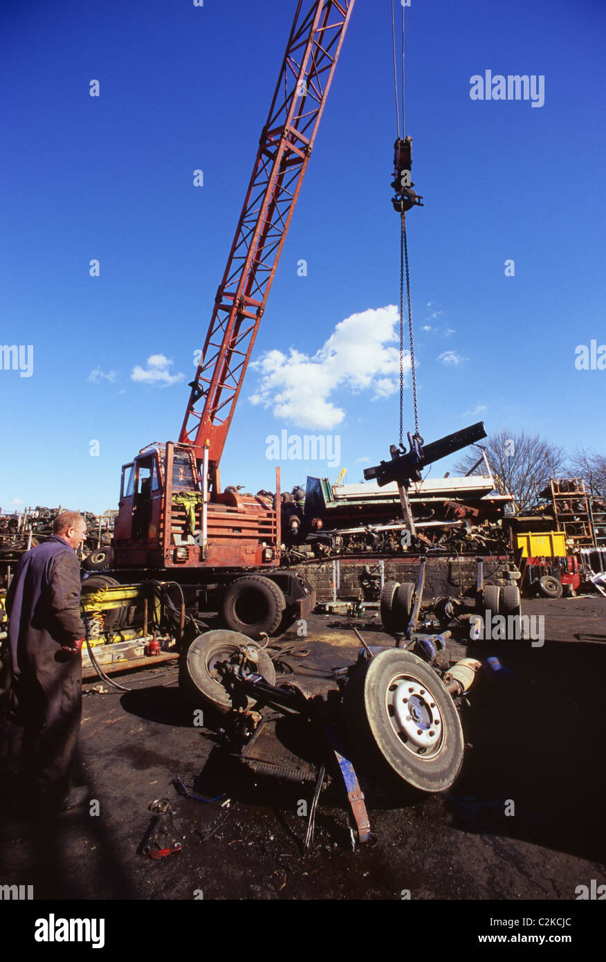 crane lifting lorry axle from lorry chassis for recycling at scrapyard ...