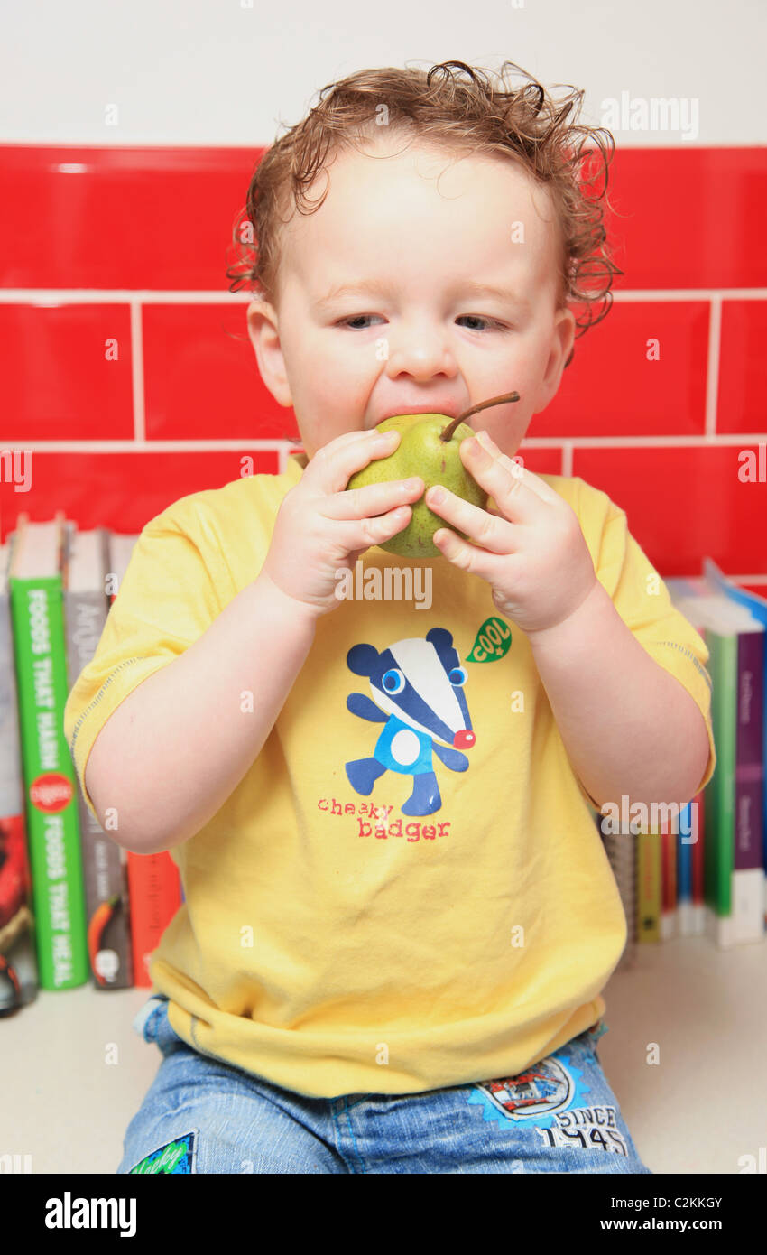 Toddler boy sitting on kitchen counter eating toast Stock Photo - Alamy