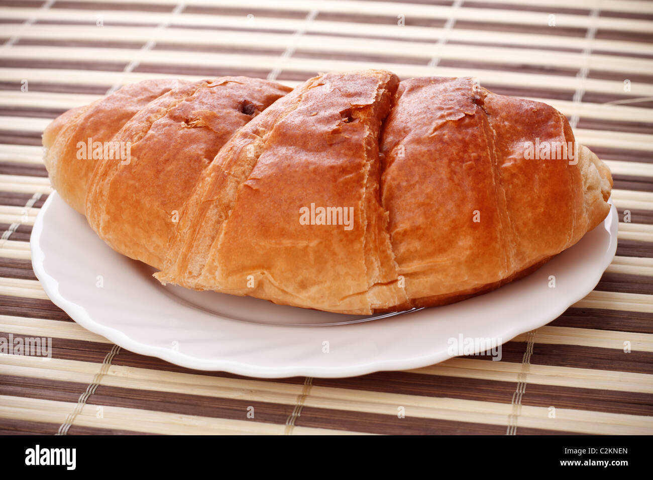 single fresh croissant laying on white dish Stock Photo - Alamy