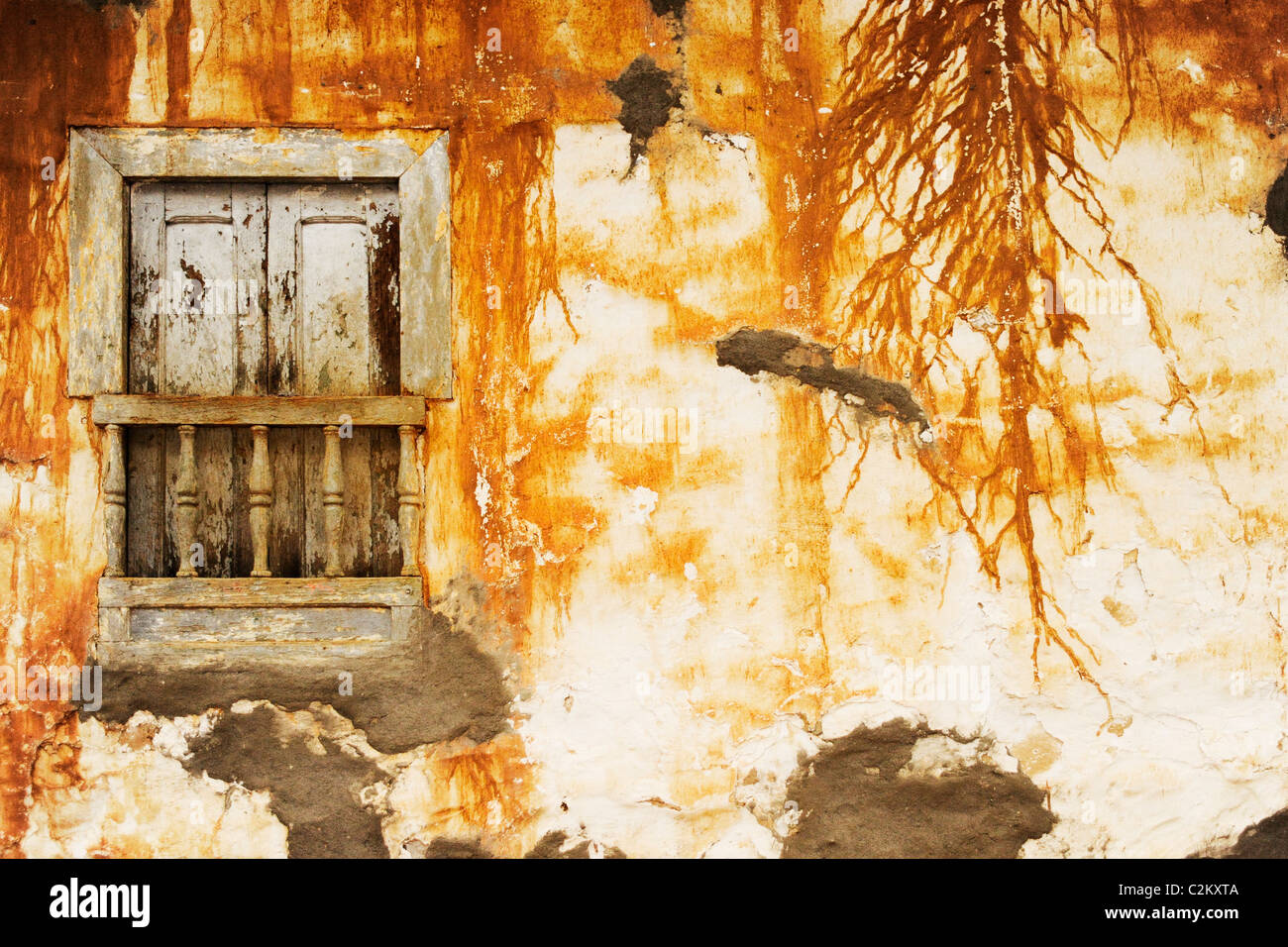 A window on a street with aged plaster work with orange dappled colour ...