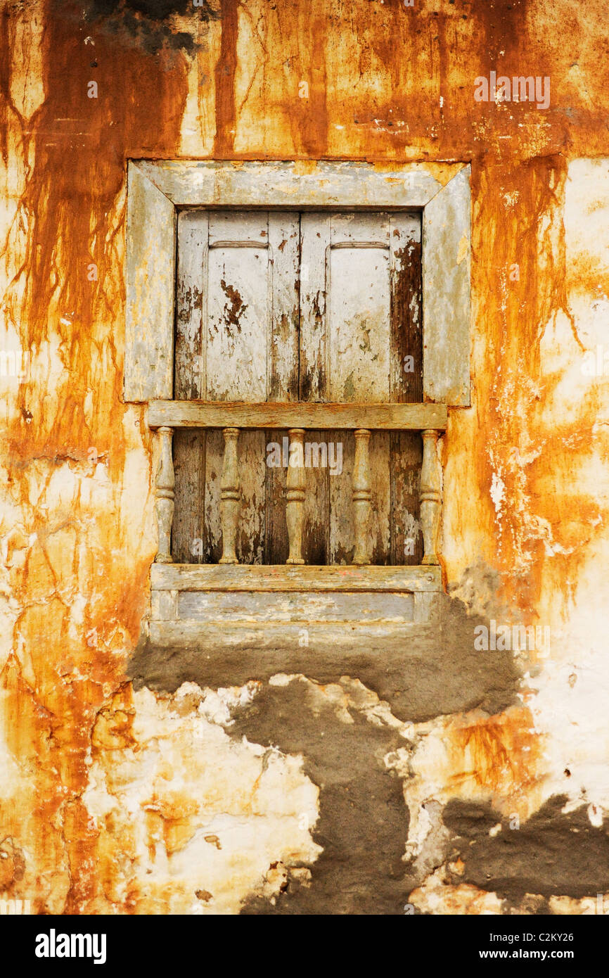 A window on a street with aged plaster work with orange dappled colour ...