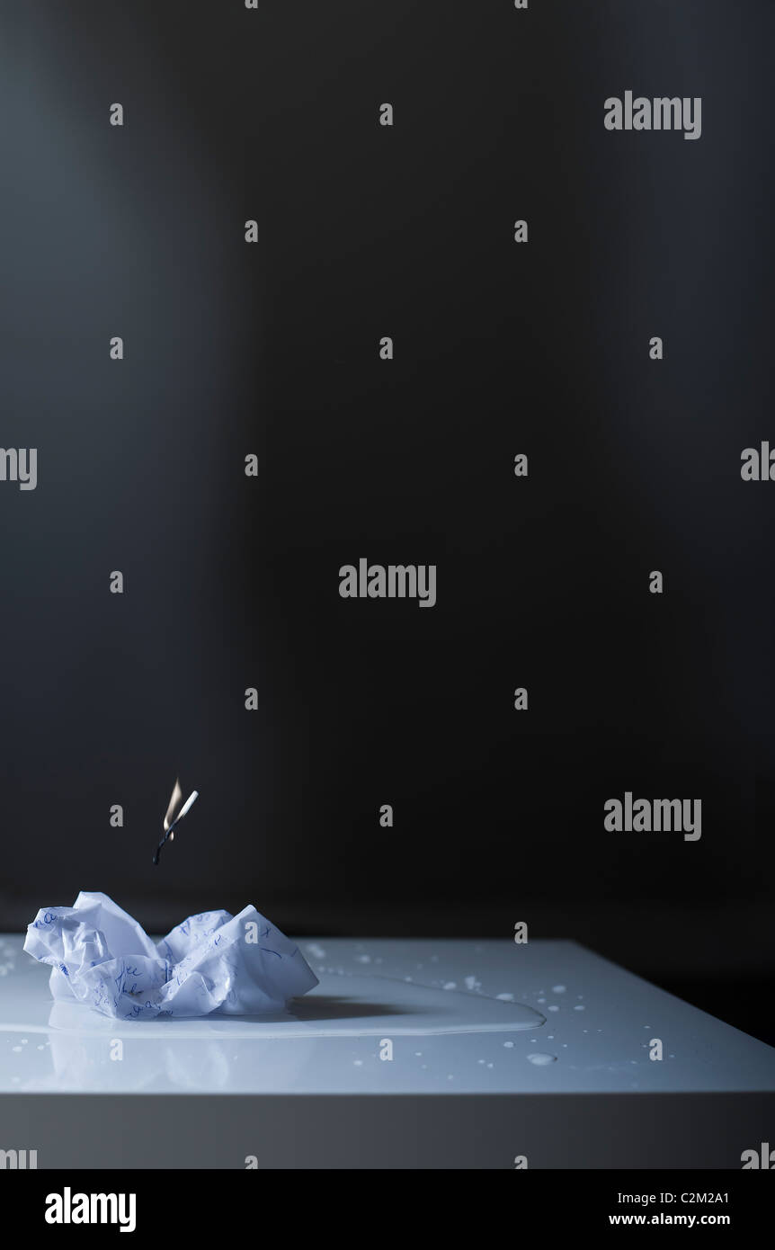 A burning match is falling down on a piece of wet paper lying on a ...