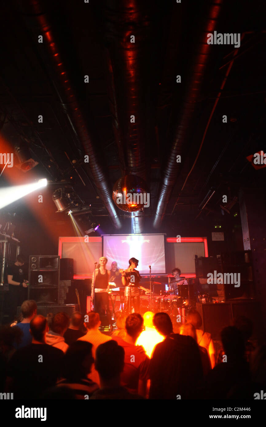A crowd of people watching live music performance lit with spotlights ...