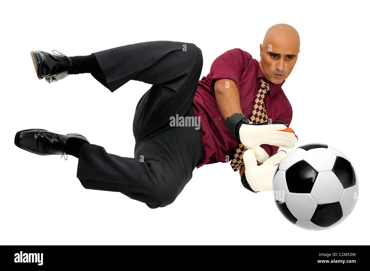 Businessman goalkeeper with gloves and ball in a acrobatic save ...