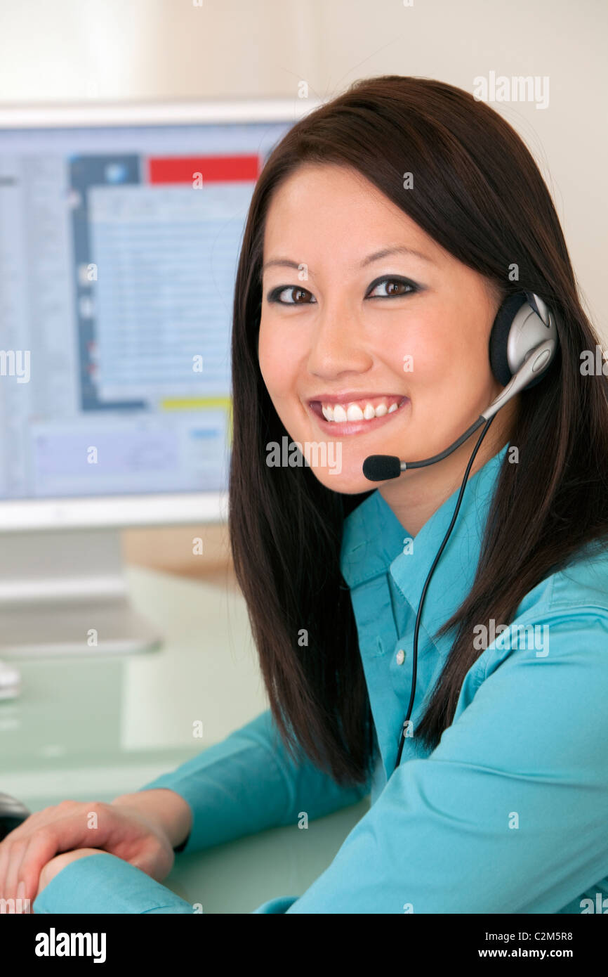 Smiling Asian woman with headset and computer monitor Stock Photo - Alamy