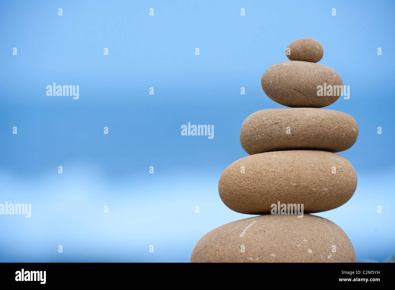 pile of balanced rocks against blue ocean background Stock Photo - Alamy