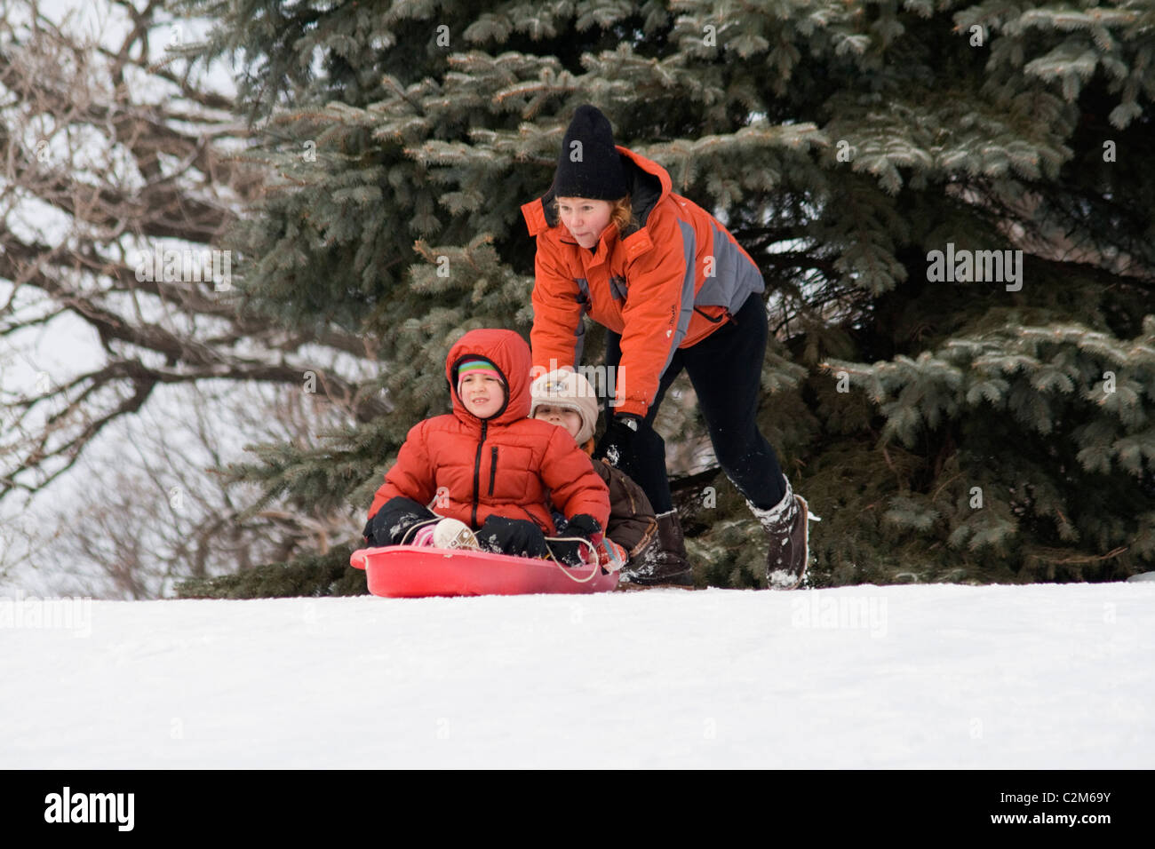 Mom age 42 pushing girl age 7 and boy age 6 on sled on snowy Merriam ...