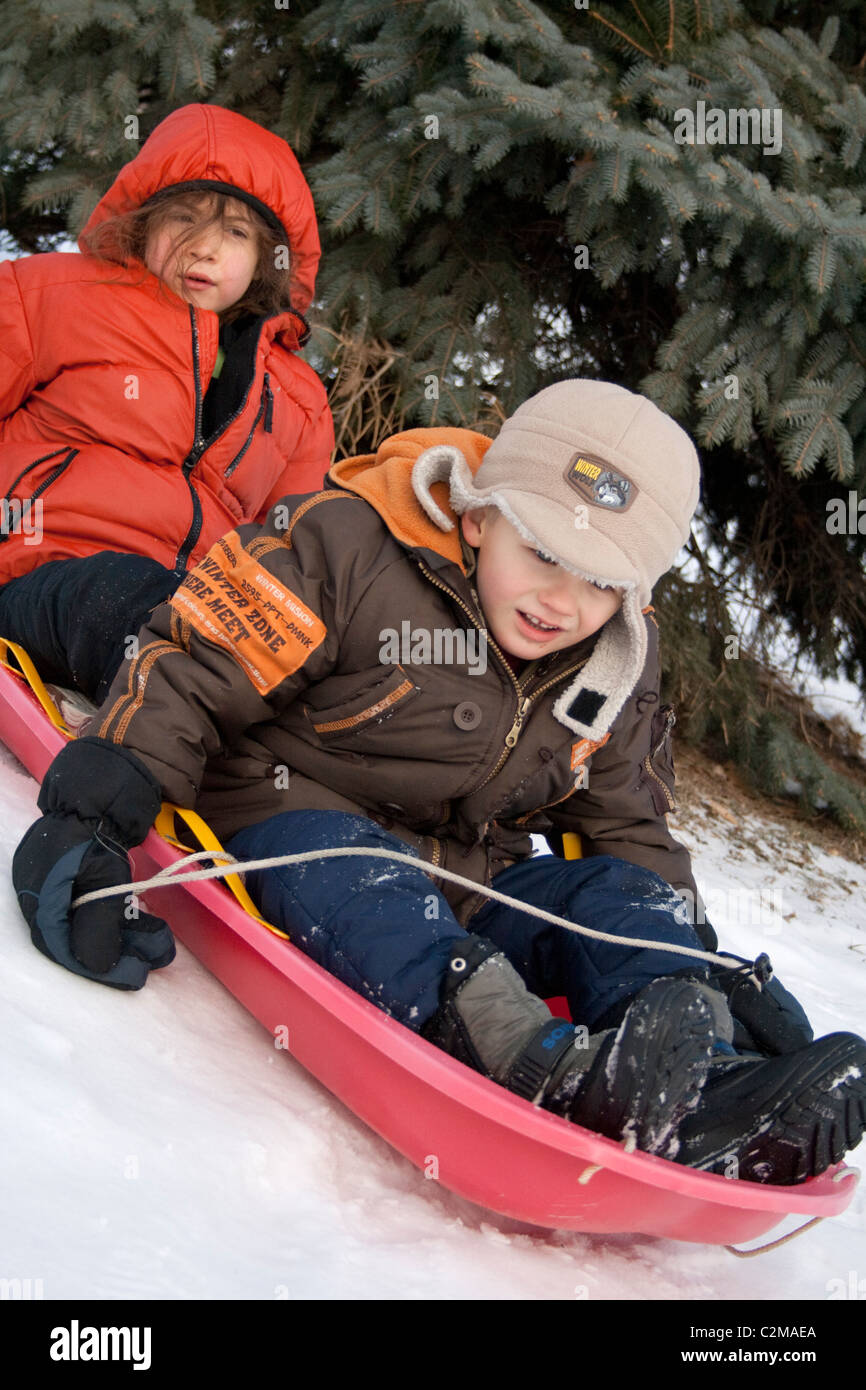 Boy and girl age 7 and 6 winter sledding on snow in Merriam Park. St ...