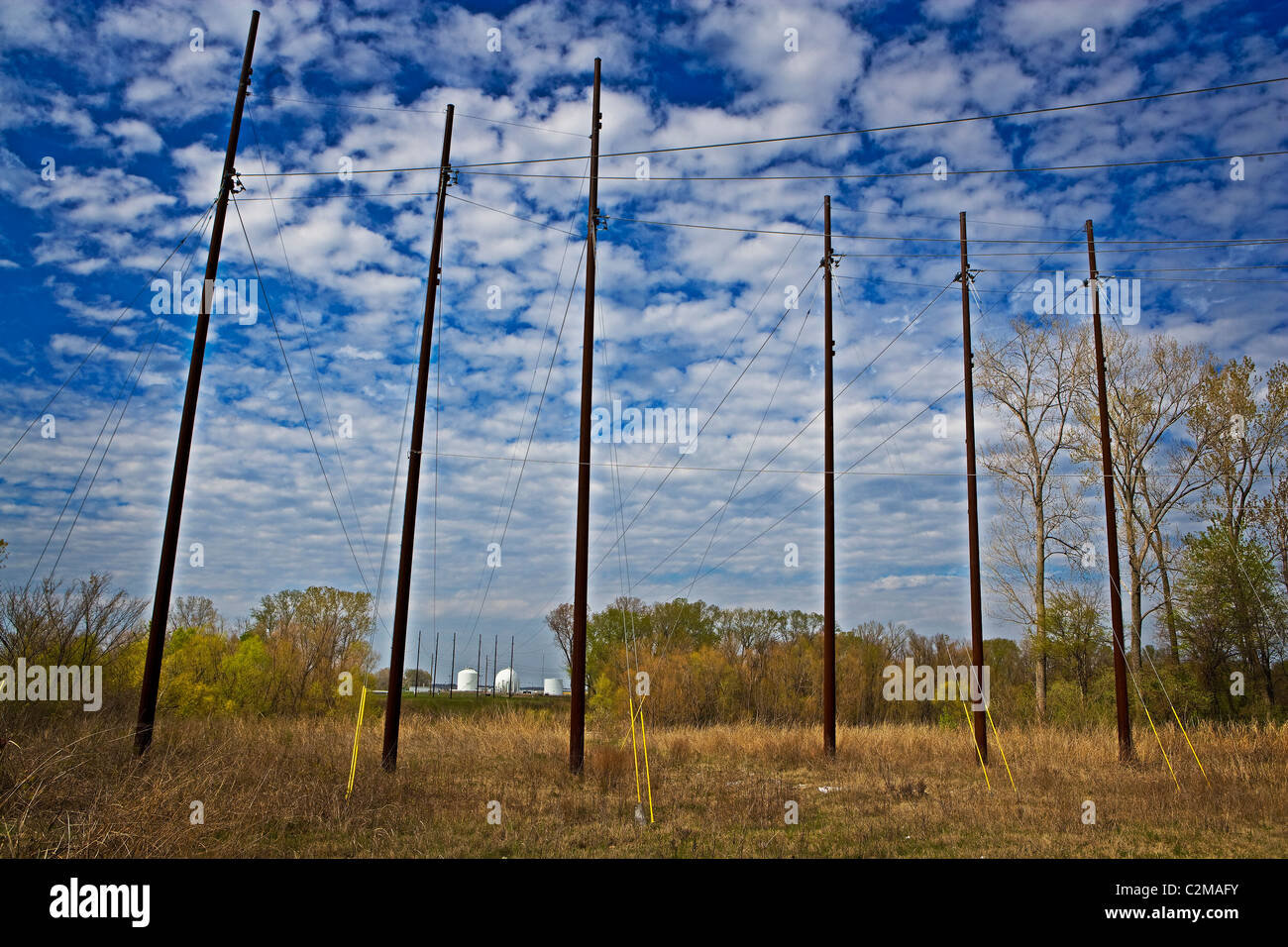 Power lines lead to a power plant in the distance with trees and ...