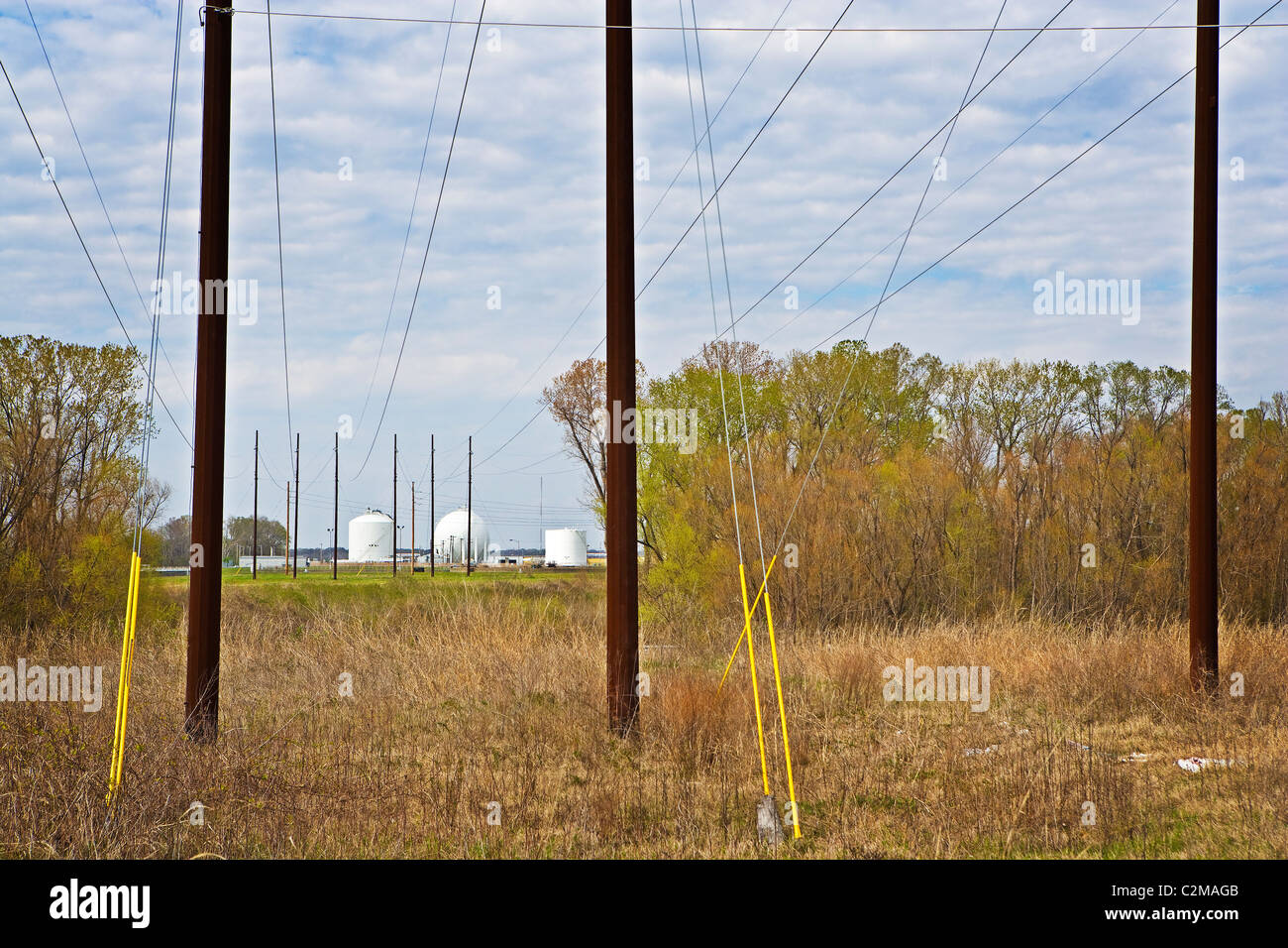 Power lines lead to a power plant in the distance with trees and ...