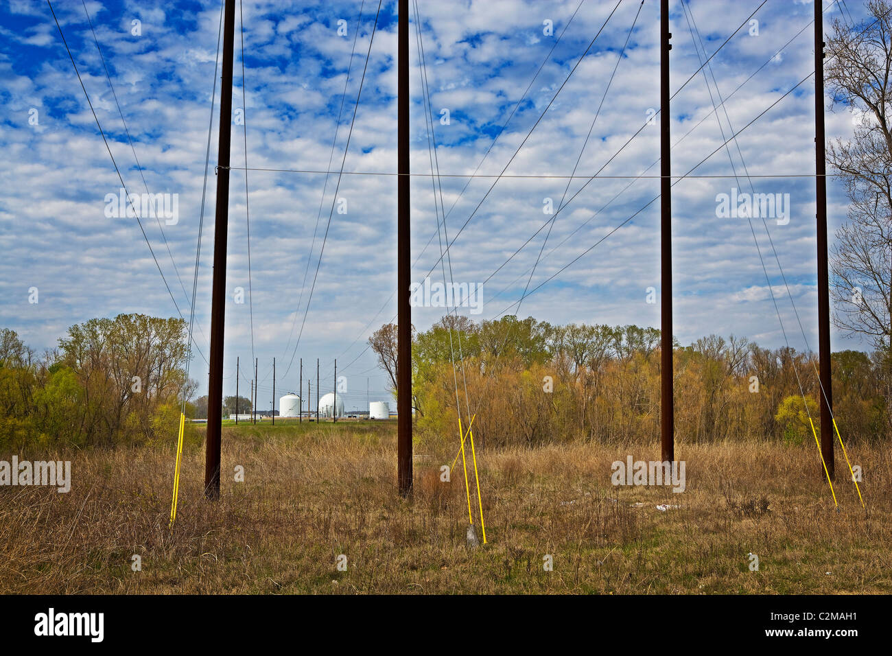 Power lines lead to a power plant in the distance with trees and ...