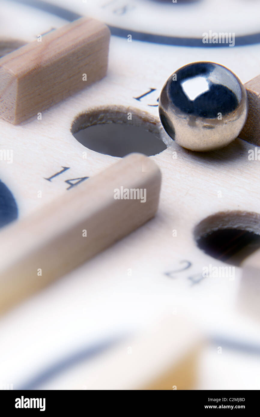 Chrome ball about to drop into a numbered hole of the wooden board game ...