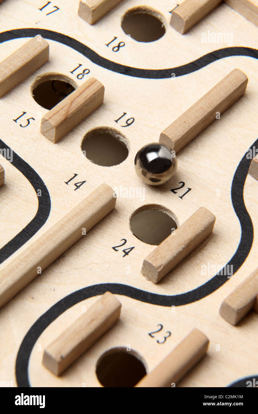 Chrome ball about to drop into a numbered hole of the wooden board game ...