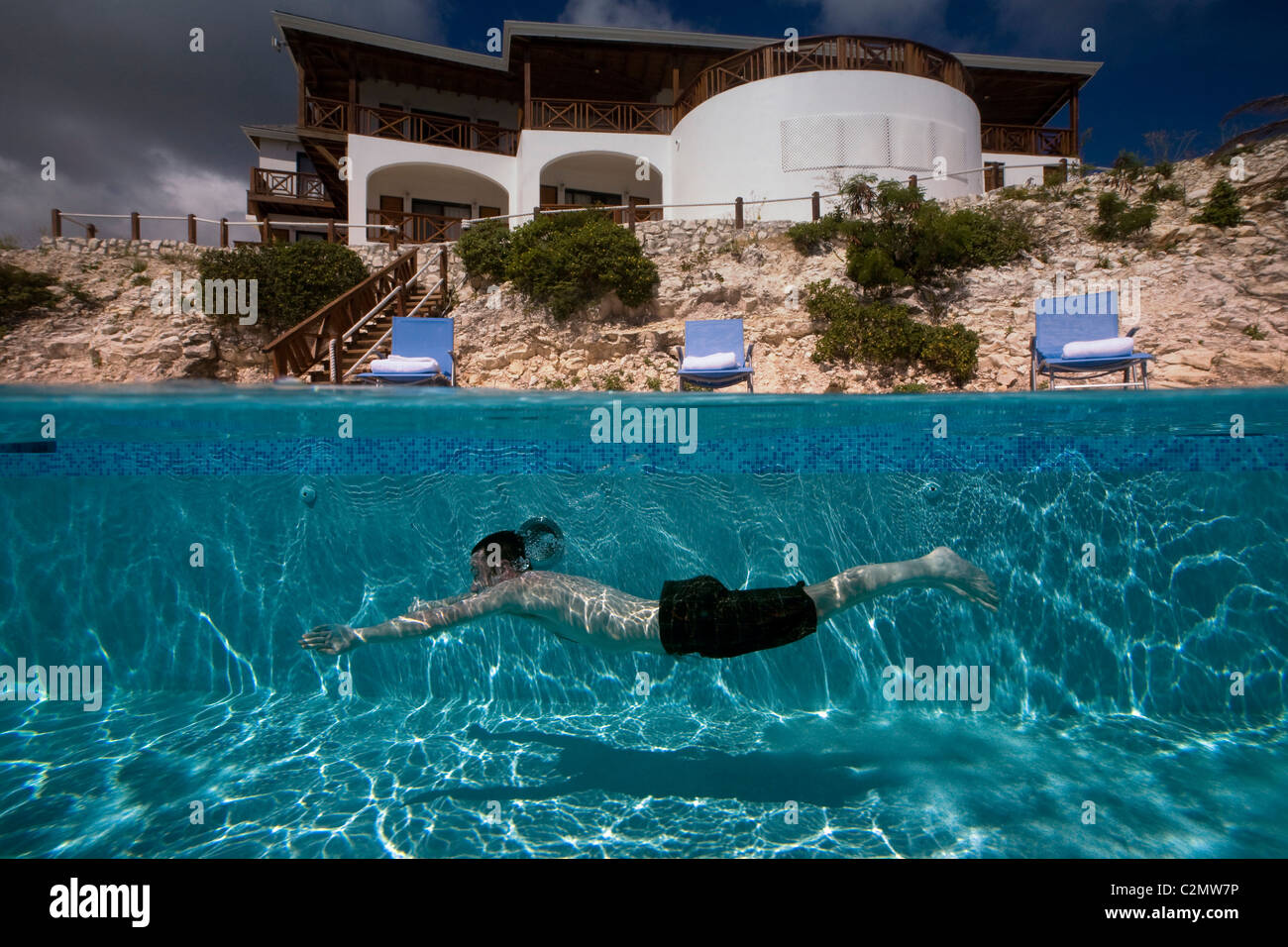 A man swims underwater in an infinity pool below a luxury villa in a ...