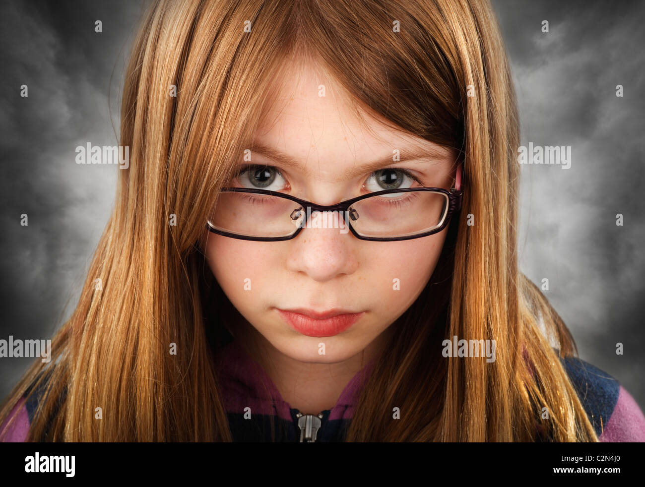 Young Girl (9) looking serious over top of her glasses, with moody ...