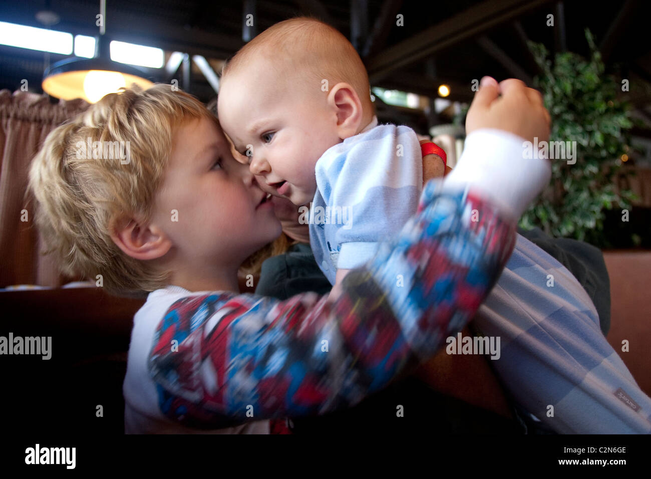 A 6 year old boy plays with his baby brother at a restaurant Stock ...