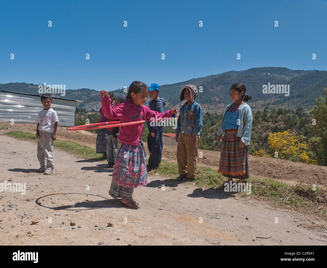 Primary school kids take a break to play with a hula hoop along a dirt ...