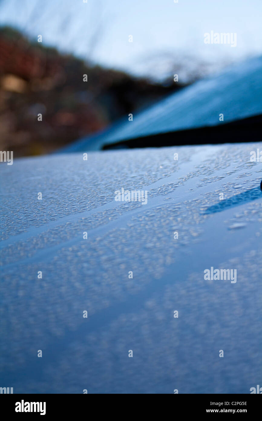 Waterdrops on car hood with blurry view of windshield during a winter ...