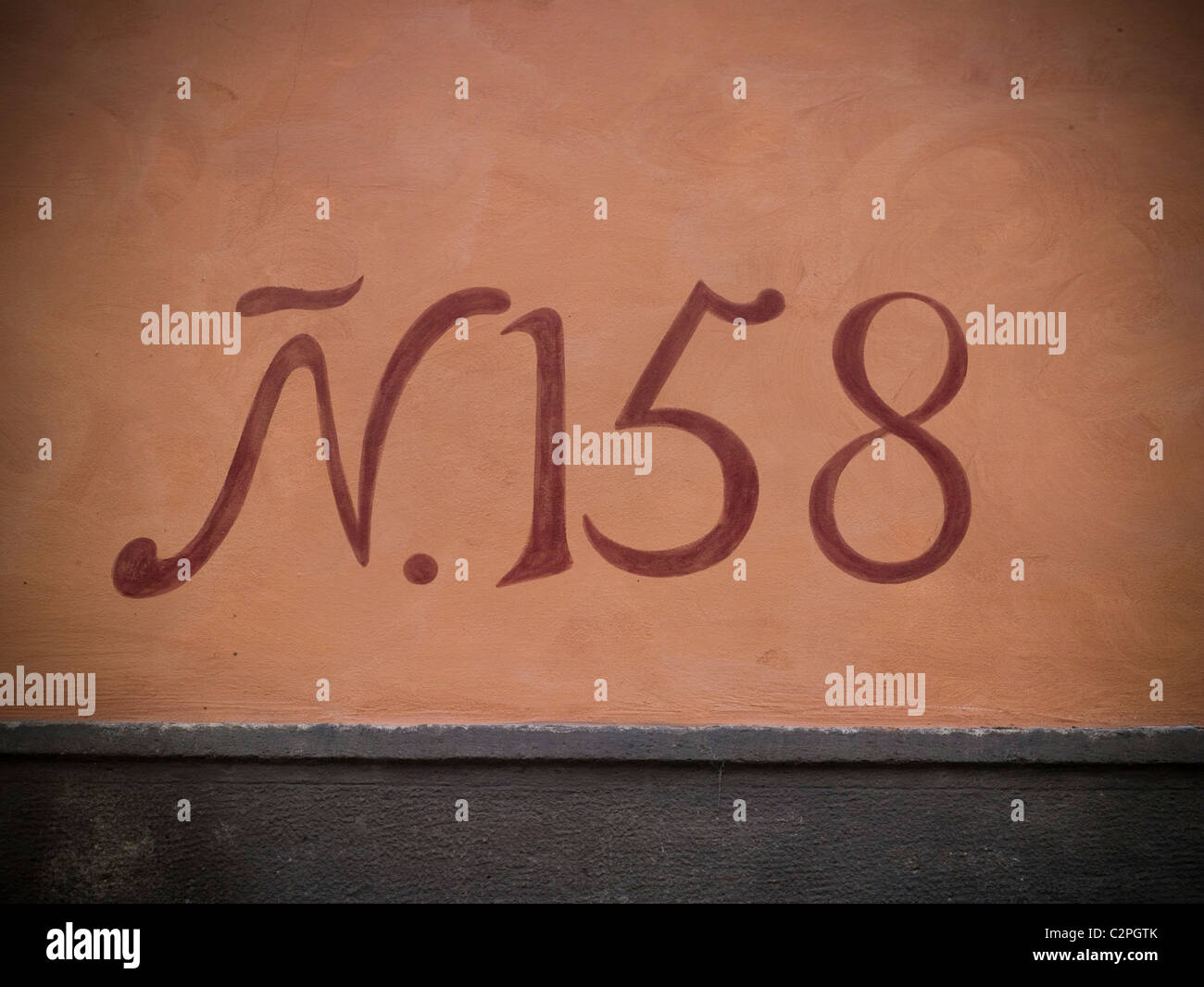 Painted house number on a terracotta coloured rendered wall Stock Photo ...