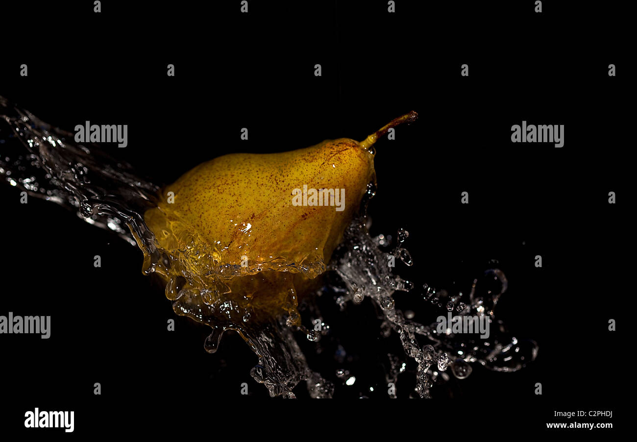 Pear with water splash on black background Stock Photo - Alamy