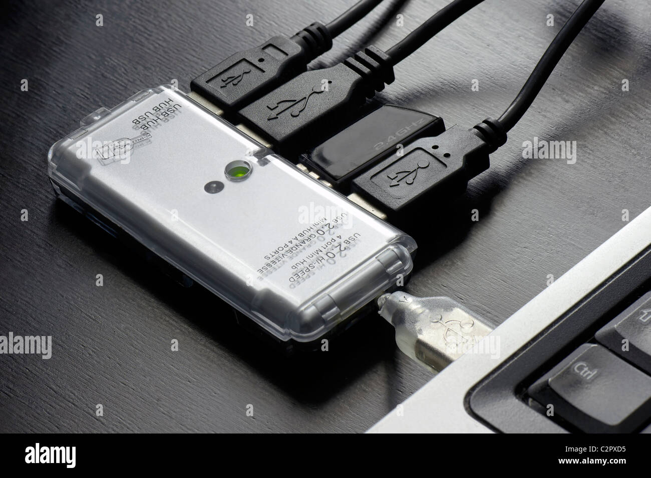 Full USB hub plugged into a laptop resting on dark wood grain office ...