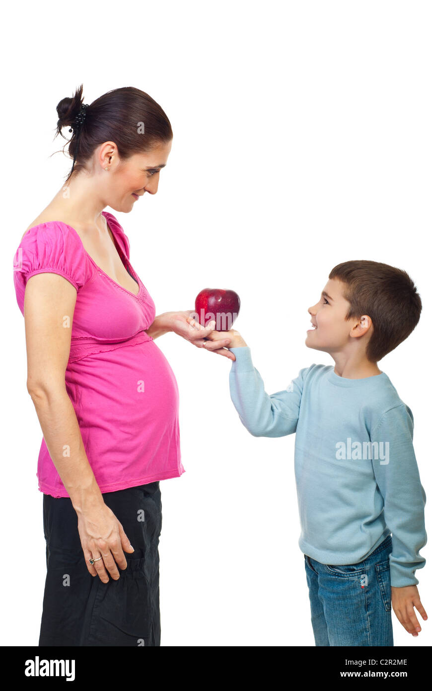 Son giving a big red apple to his pregnant mother and smiling together ...