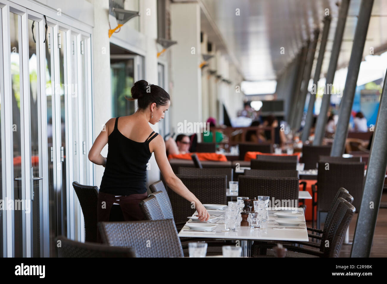 Waitress setting table at a waterfront restaurant. The Pier, Cairns ...
