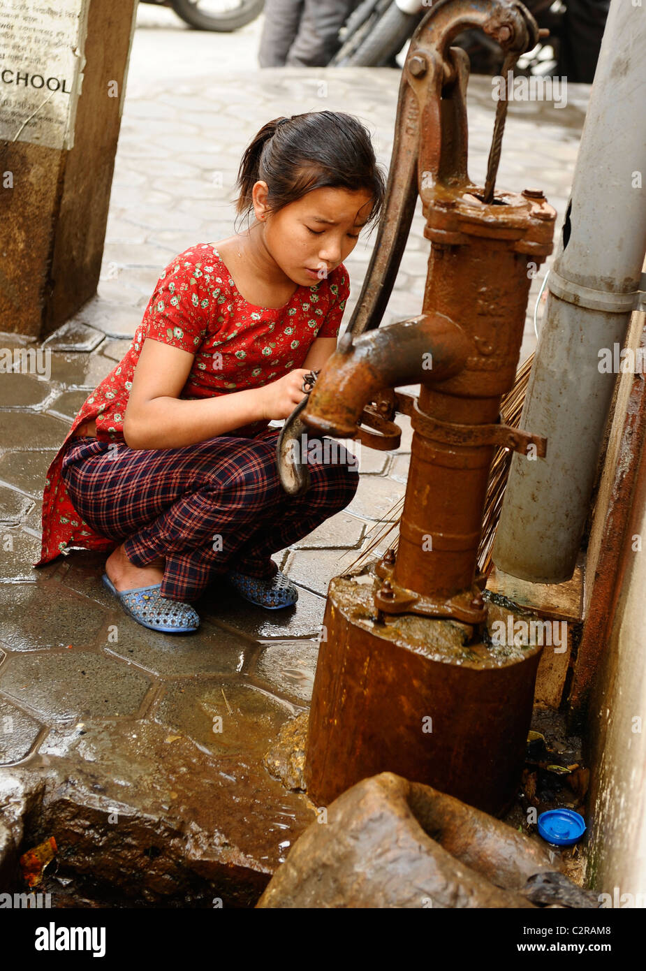 young girl collecting water from communal water pump, kathmandu street ...