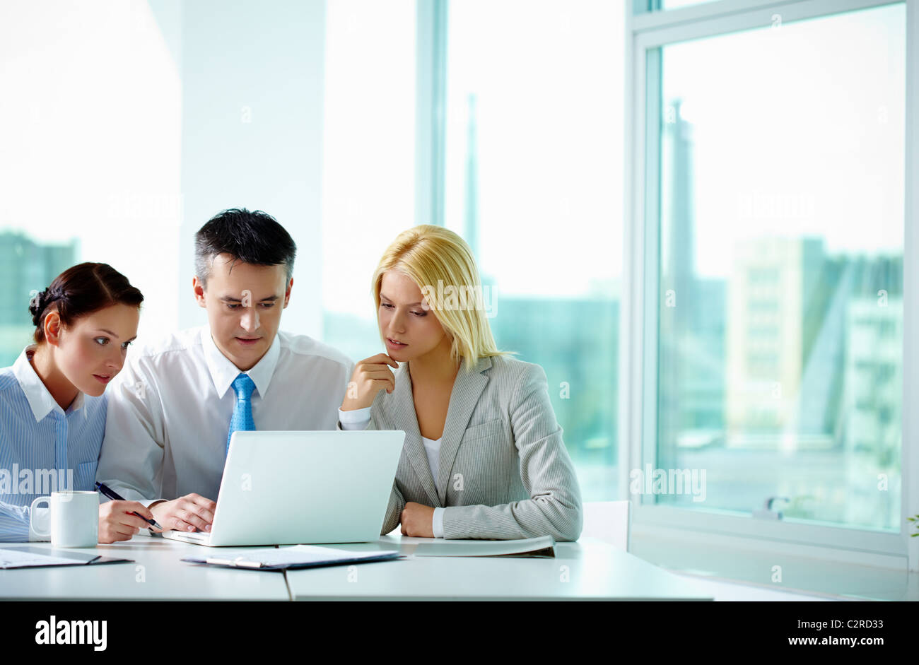 Portrait of several colleagues looking at laptop screen in office Stock ...