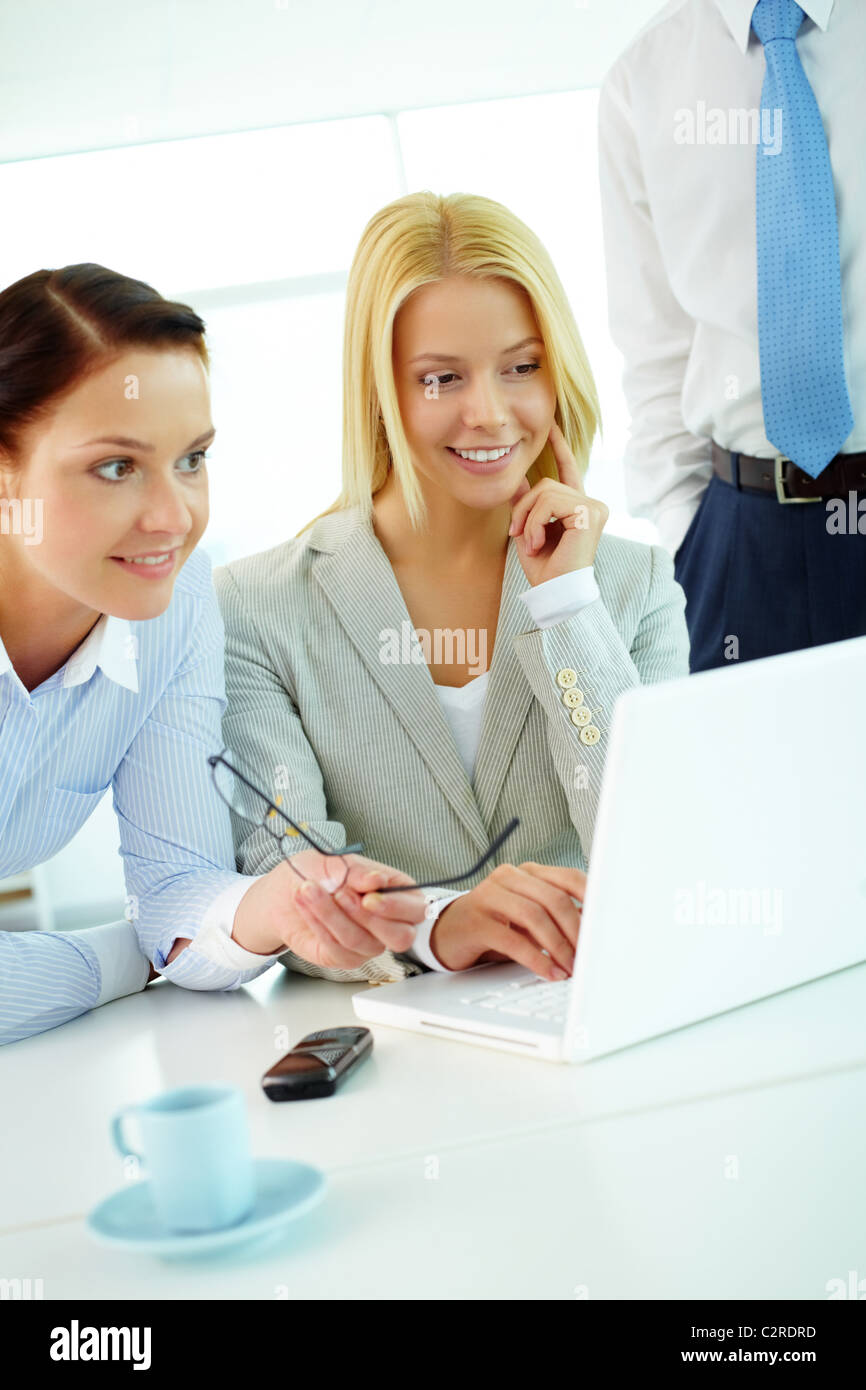 Portrait of pretty colleagues looking at laptop screen in office Stock ...