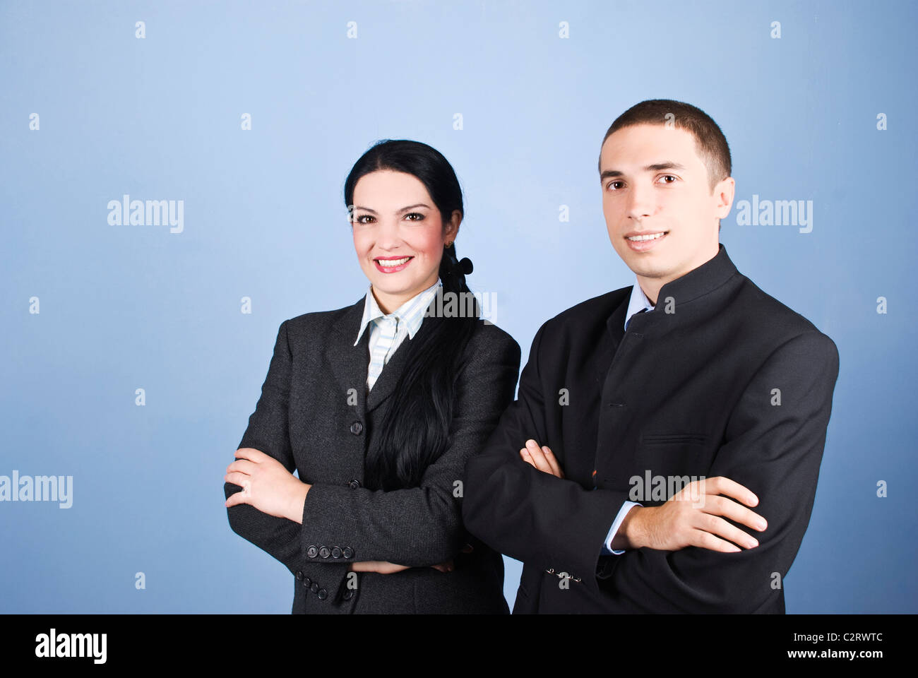 Two cheerful young business people standing with arms folded and ...