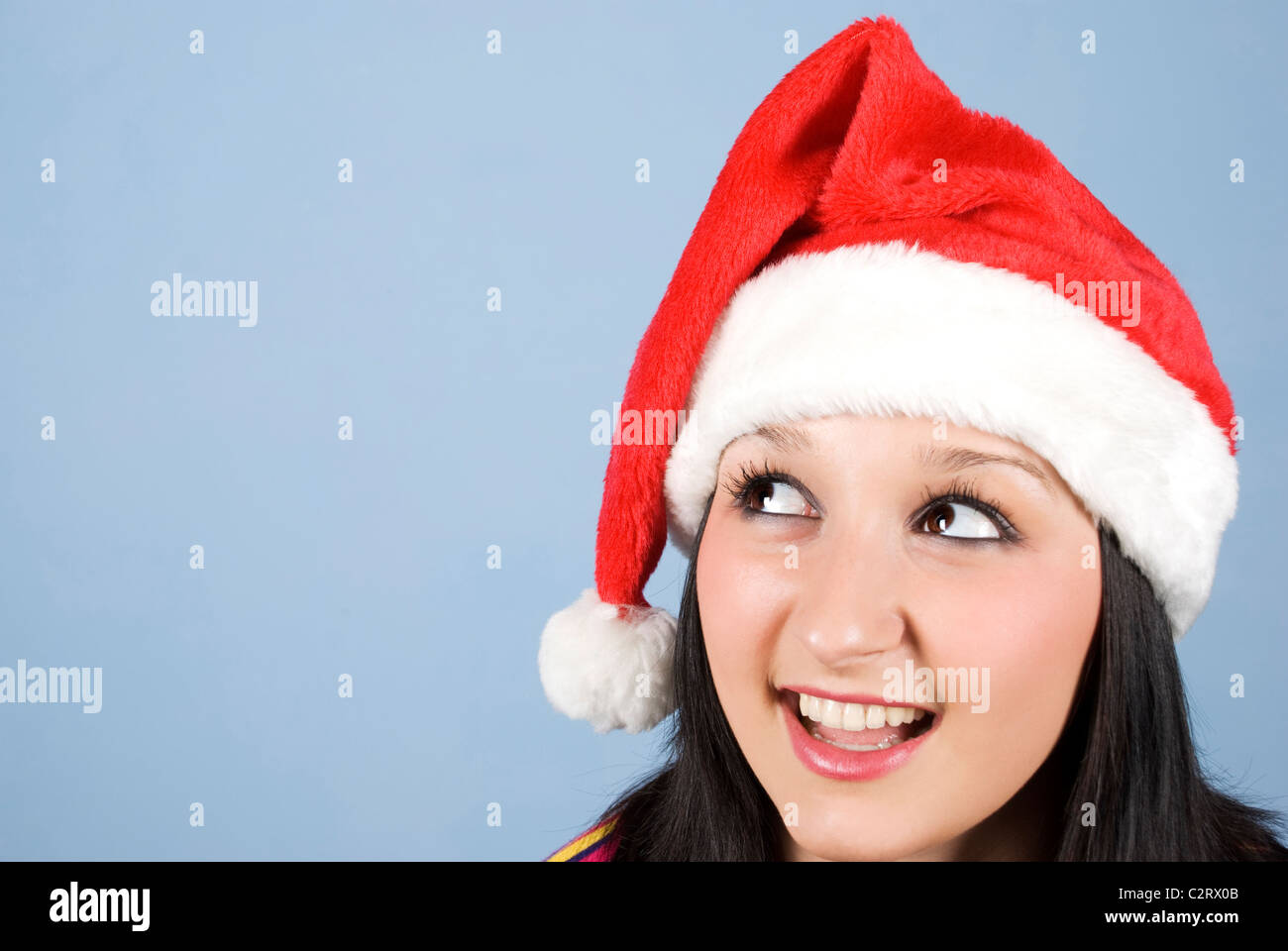 Head shot of young female with santa hat looking sideways upper left ...