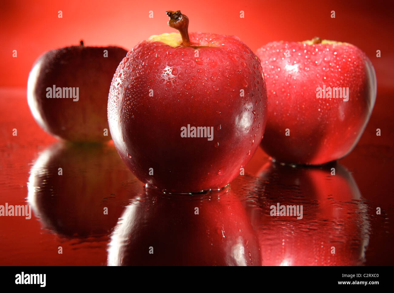 Three red apples on the mirror with droplets with red background Stock ...