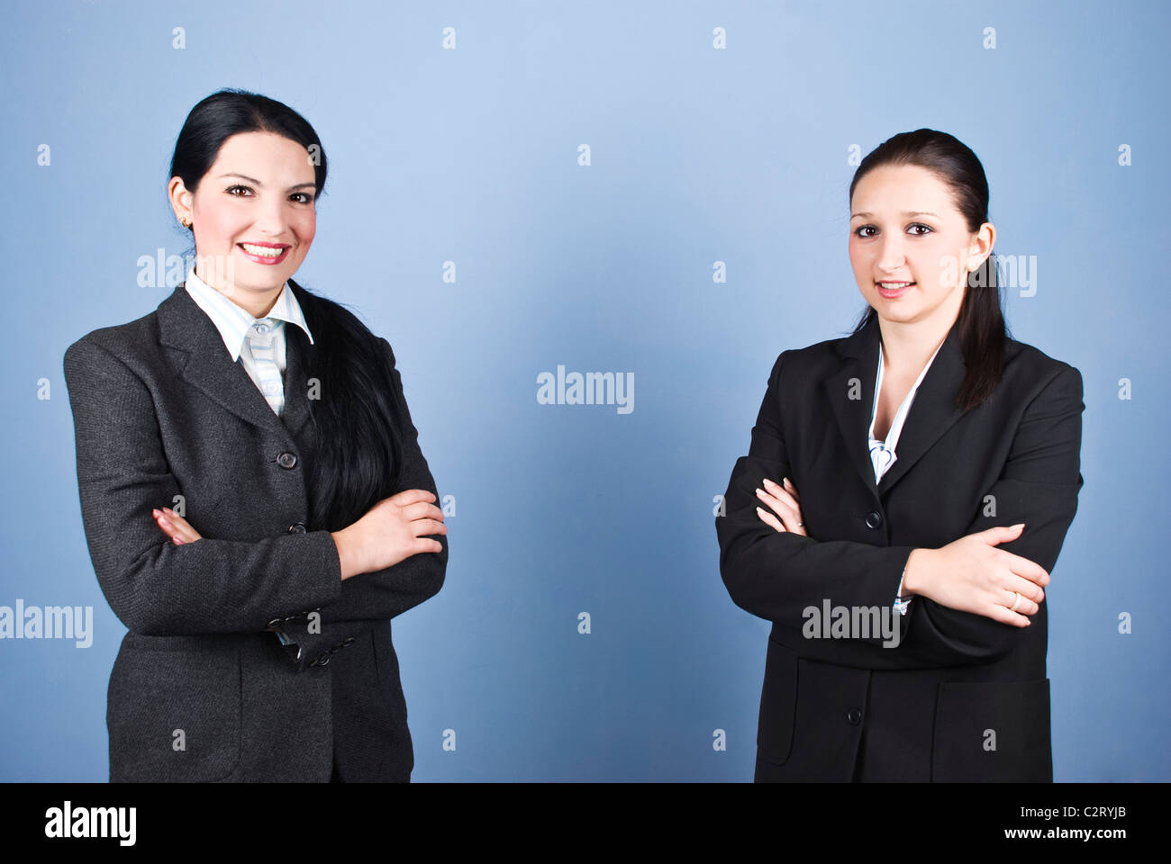 Two business women standing with arms folded and smiling,copy space for ...
