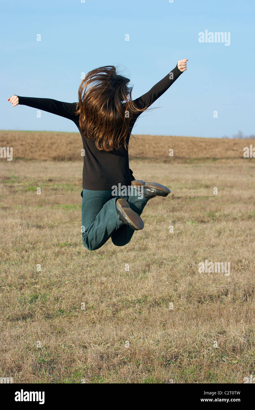 Happy girl jumping around on a dry field Stock Photo - Alamy