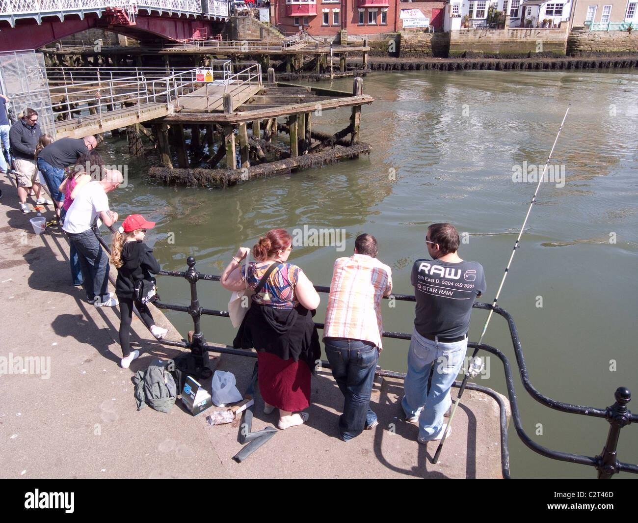 Holidaymakers in spring sunshine fishing by the bridge in Whitby ...