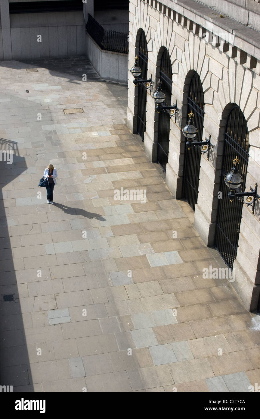 Lone woman walking along embankment under London Bridge Stock Photo - Alamy
