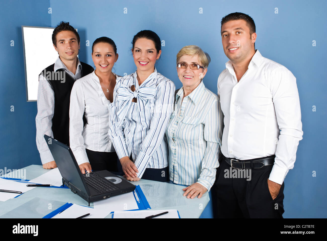 Group of five business people standing in a line and smiling in a ...